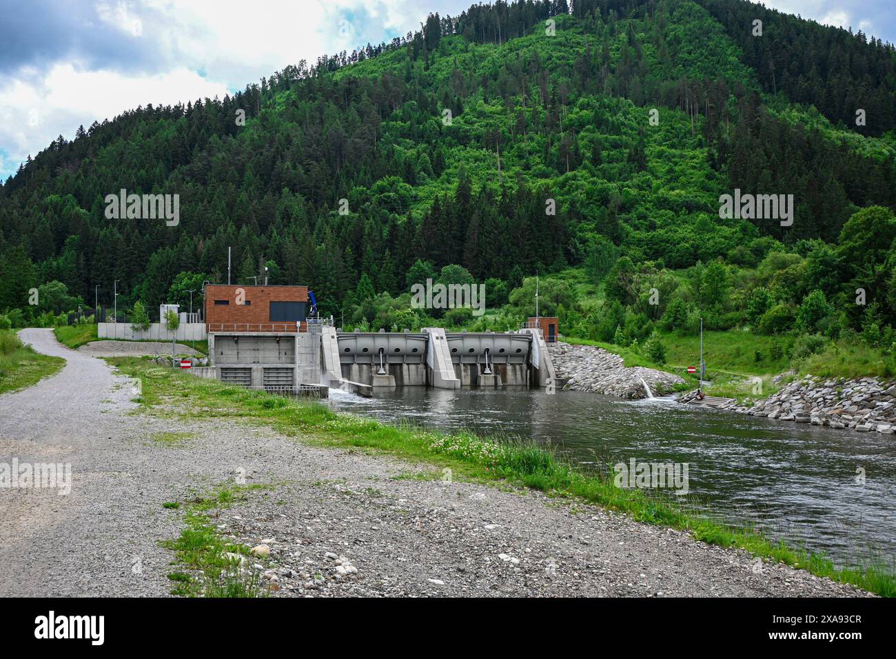 Small hydroelectric dam operates in a forested area, exemplifying ...