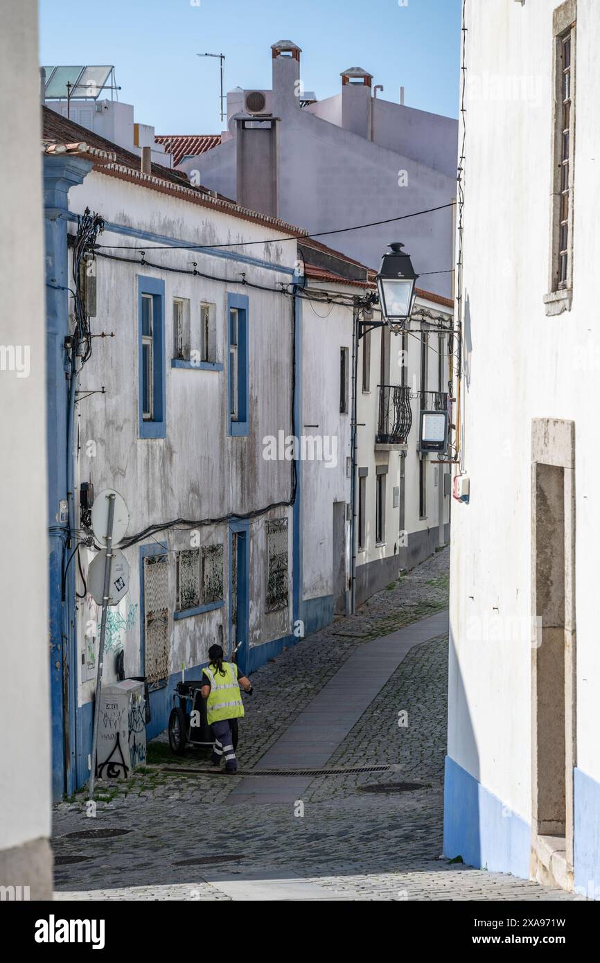 Worker pushing a cart down the street in the Town of Sines, Setubal ...