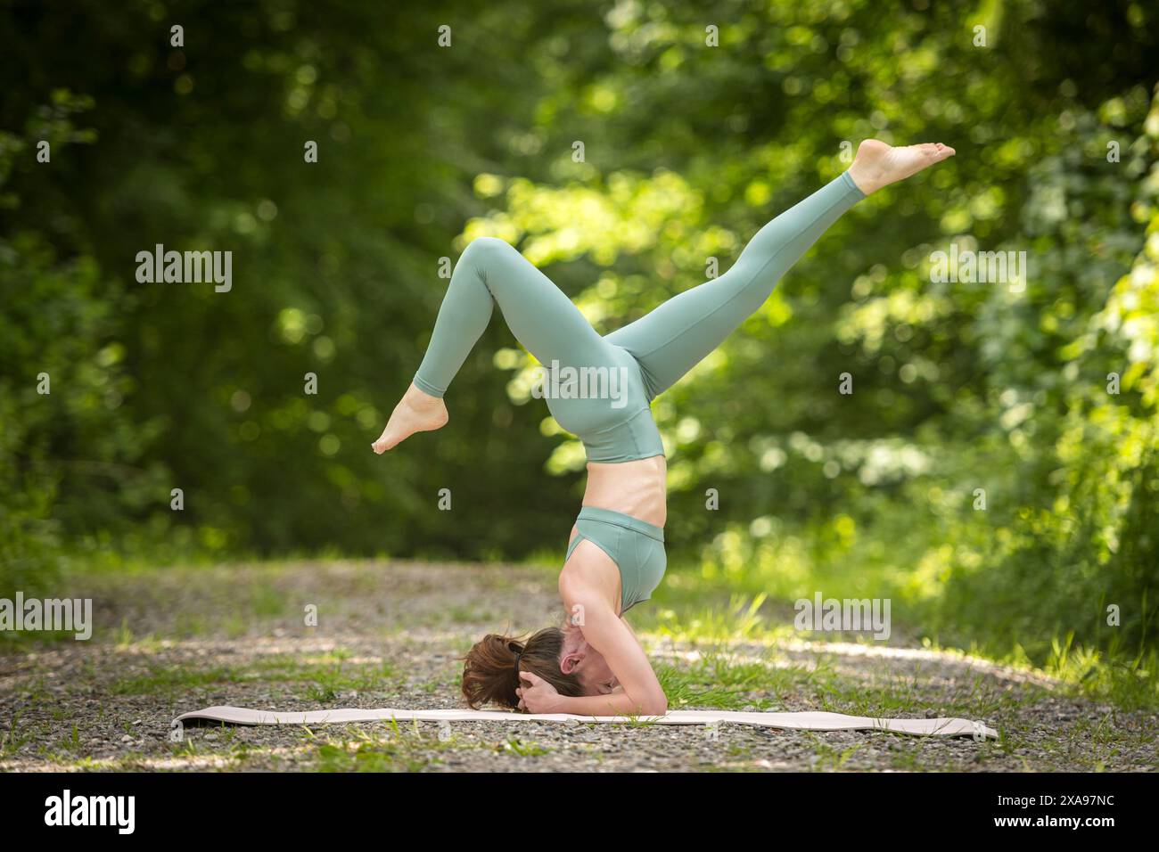 Sporty woman doing a headstand in the park, outddor exercise concept ...