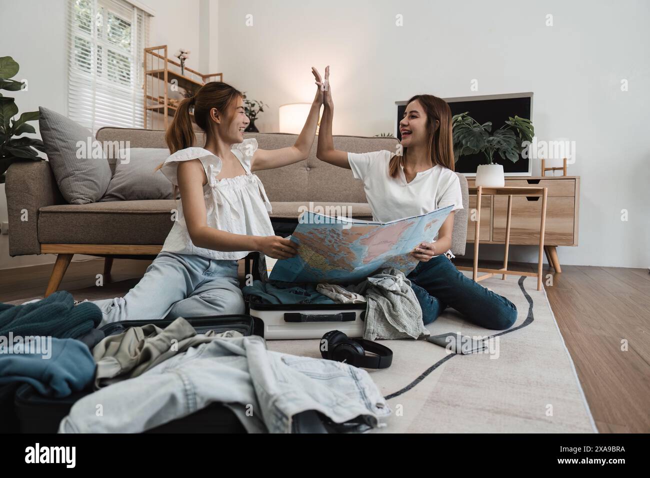 Two Young Women Planning Trip with Map and Suitcases Indoors, Concept ...