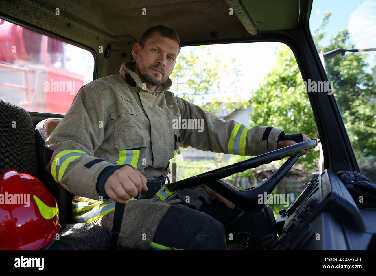 Firefighter in uniform driving modern fire truck Stock Photo - Alamy