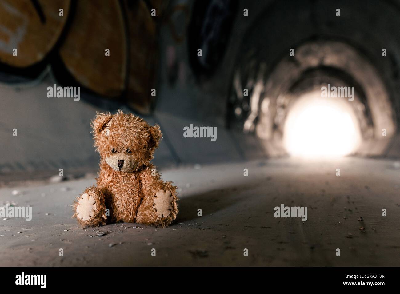 Homeless lonely poor teddy bear sitting in dark tunnel under the bridge ...