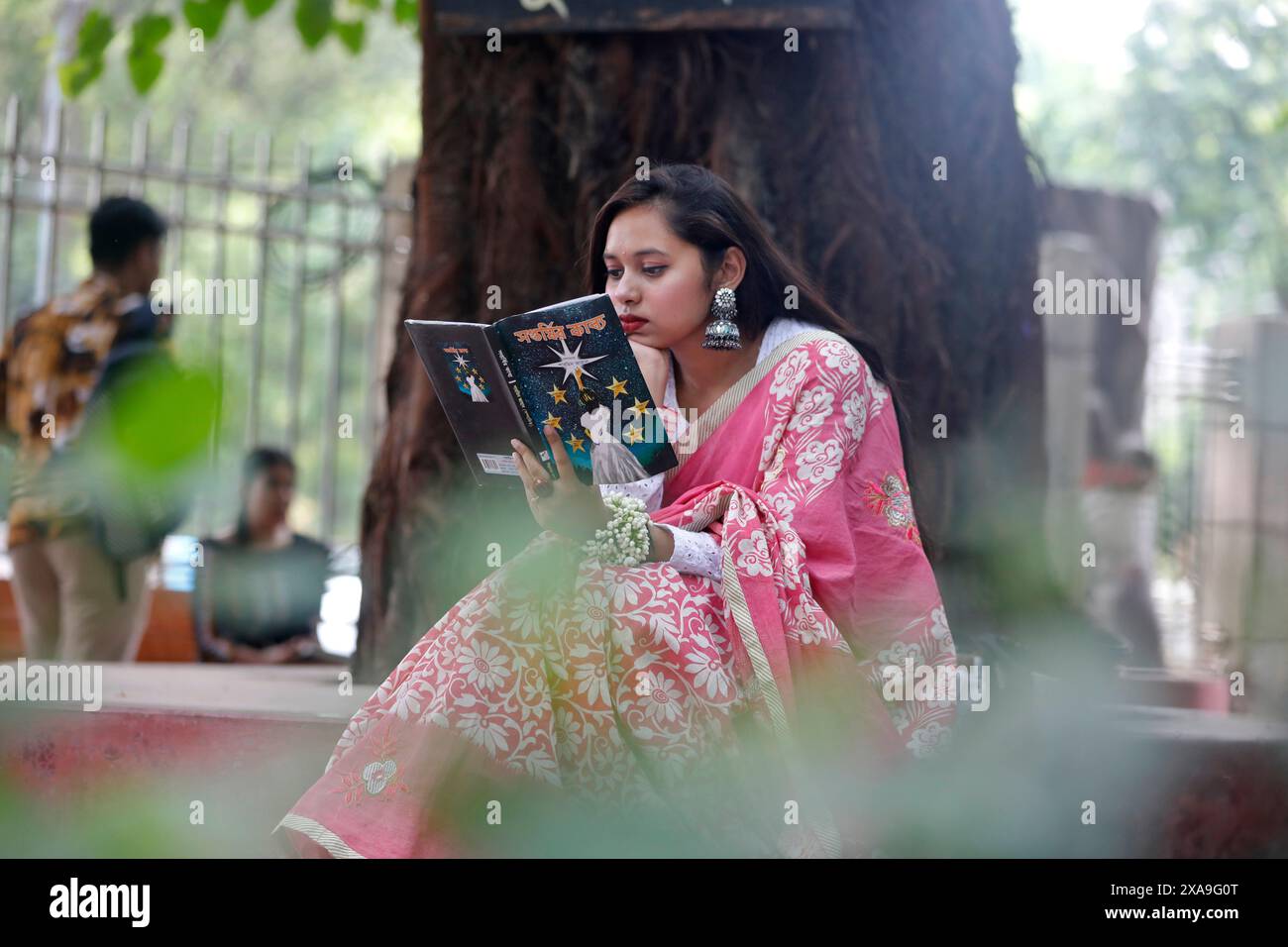 Dhaka, Bangladesh - May 23, 2024: A student reading a book sitting in an open library in Dhaka ...