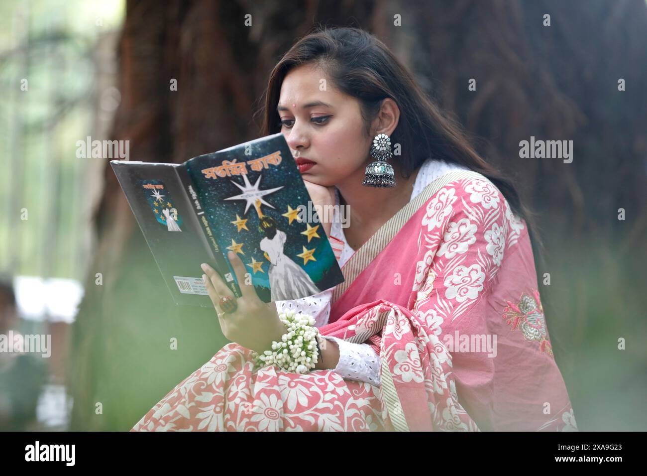 Dhaka, Bangladesh - May 23, 2024: A student reading a book sitting in an open library in Dhaka ...