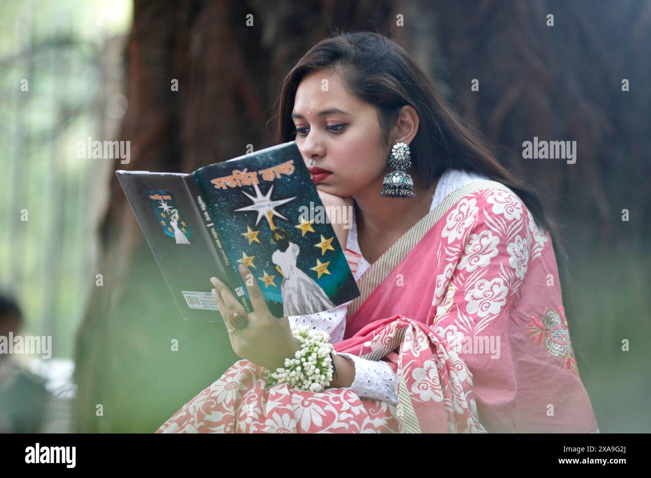 Dhaka, Bangladesh - May 23, 2024: A student reading a book sitting in an open library in Dhaka ...