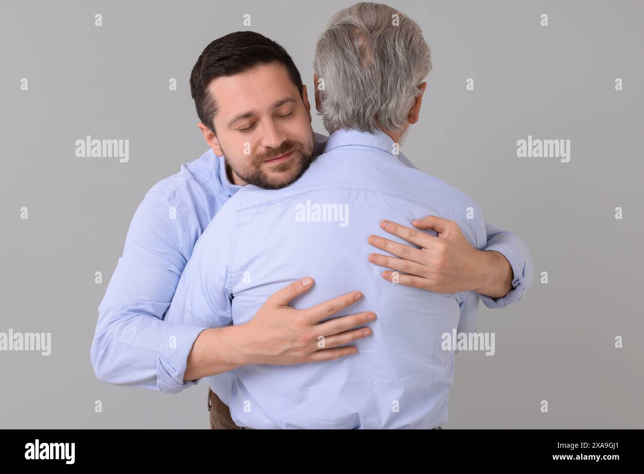 Happy son and his dad hugging on gray background Stock Photo - Alamy
