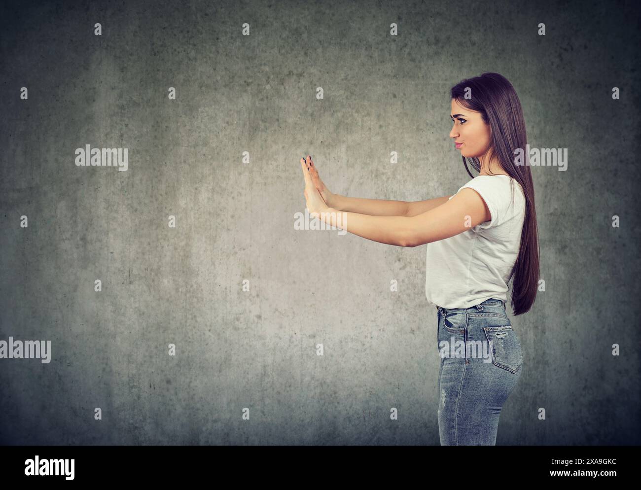 woman pushing with hands an invisible obstacle or showing a stop hand ...