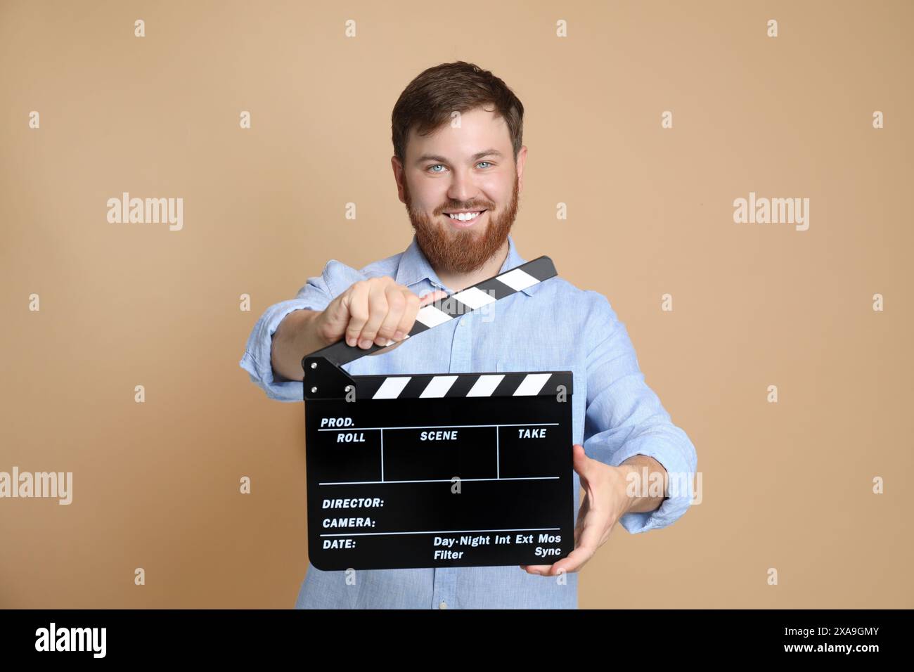 Making movie. Smiling man with clapperboard on beige background Stock ...