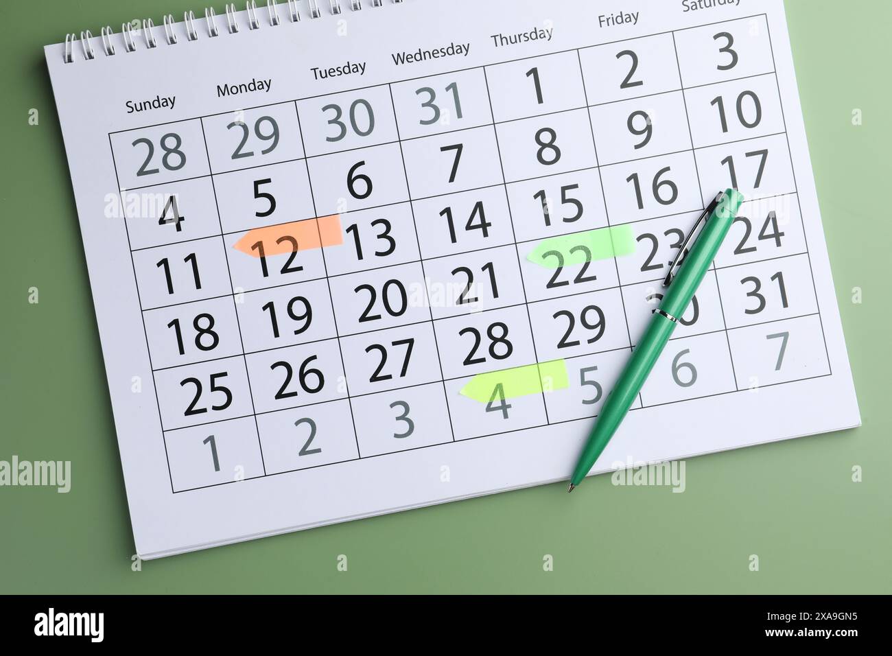 Timetable. Calendar page with marked dates and pen on green background ...