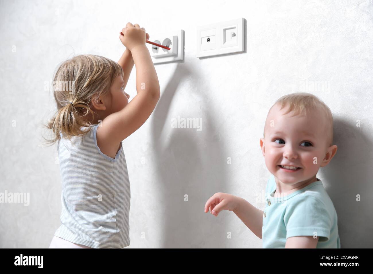 Little children playing with electrical socket indoors. Dangerous ...