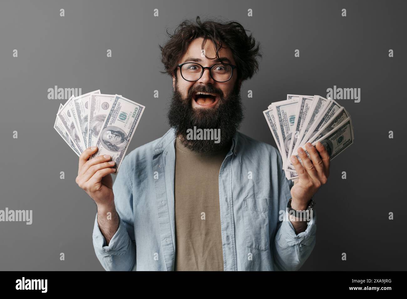 Bearded man excitedly holding multiple cash bills Stock Photo - Alamy