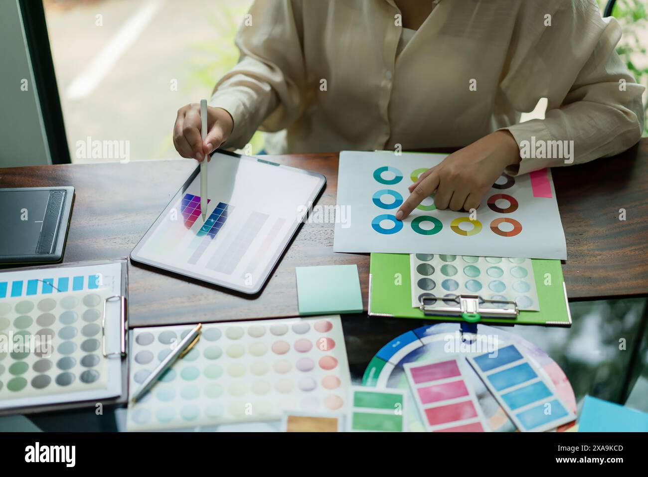 Creative graphic designer comparing color swatch on tablet and document ...