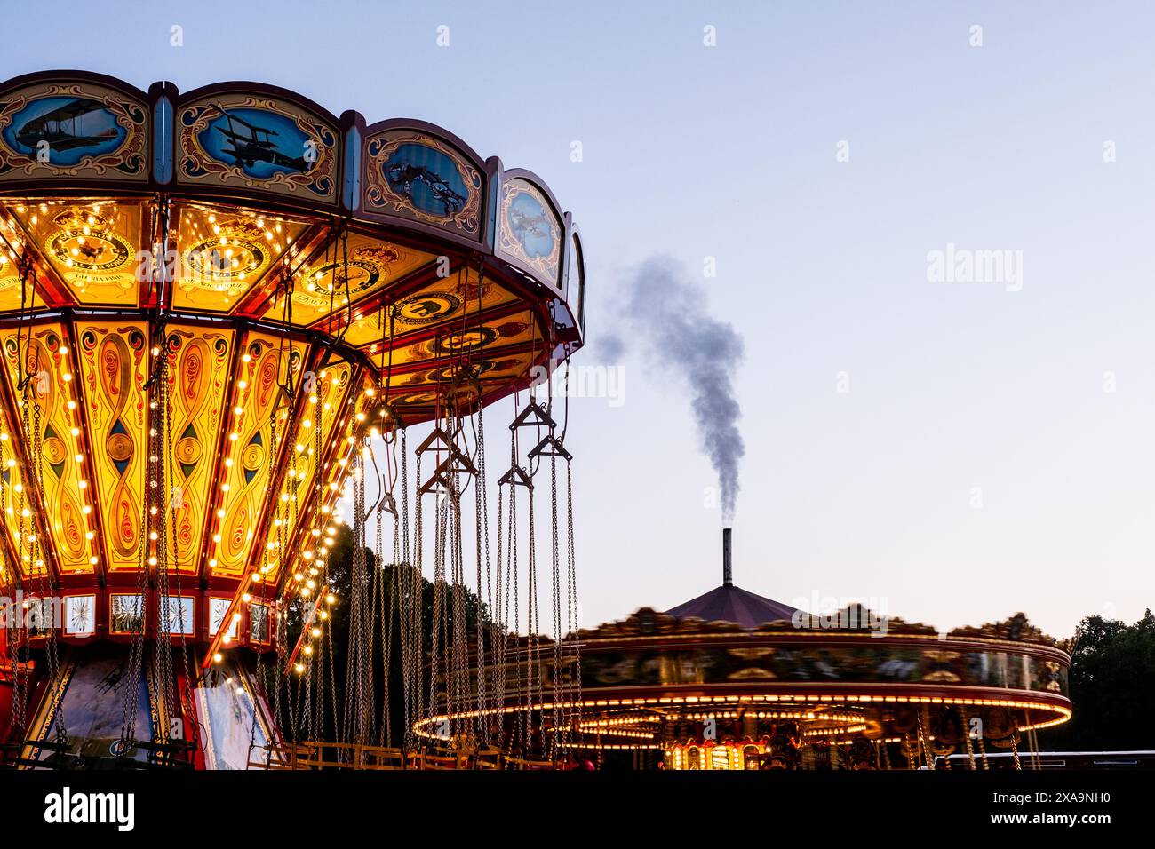Amusement rides lit up against a cloudy night sky for passengers Stock ...