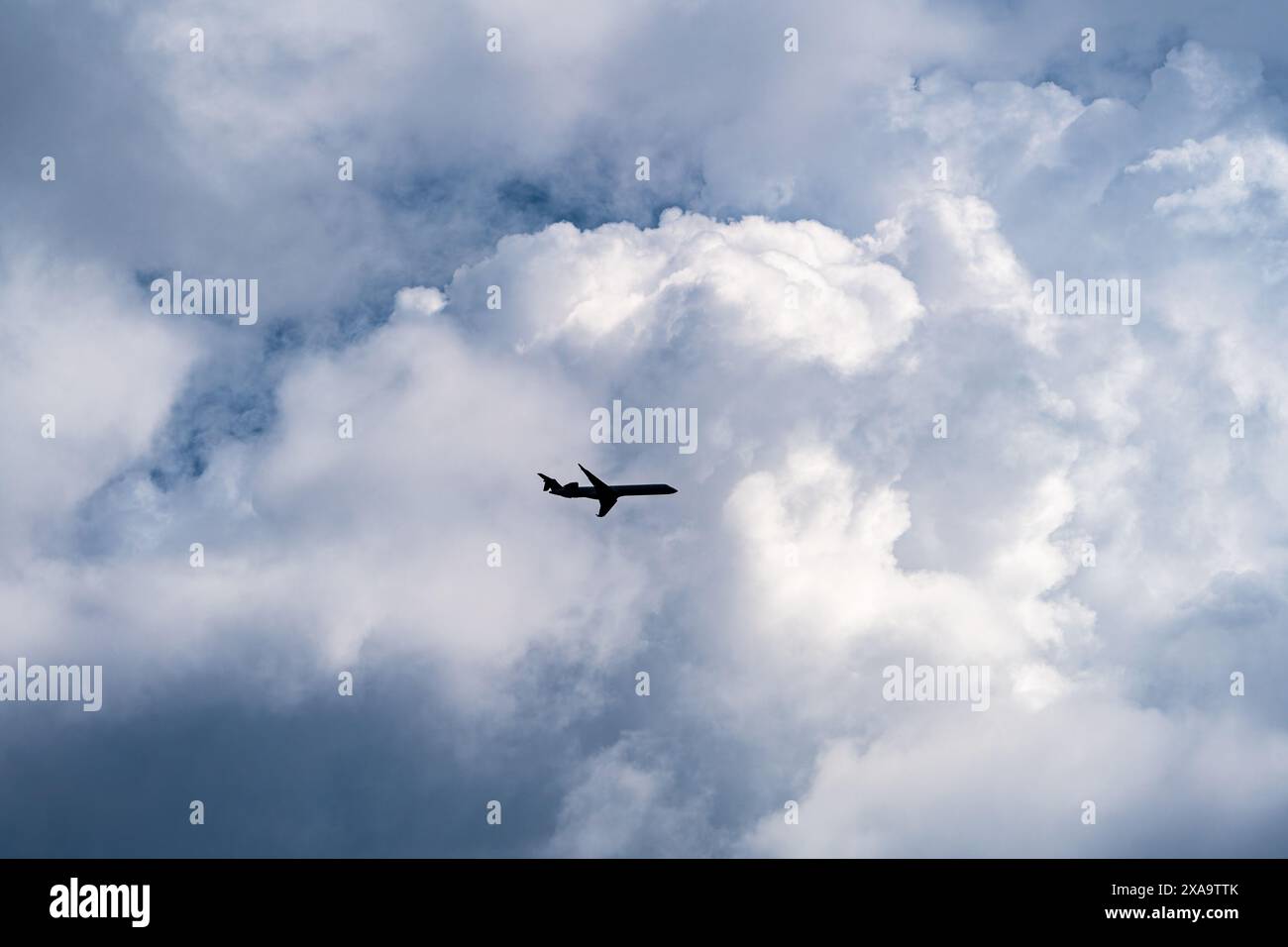A small airplane flying amidst large clouds in a blue sky Stock Photo ...