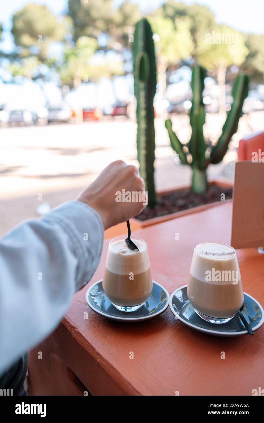 Two cups and hands holding utensils Stock Photo - Alamy