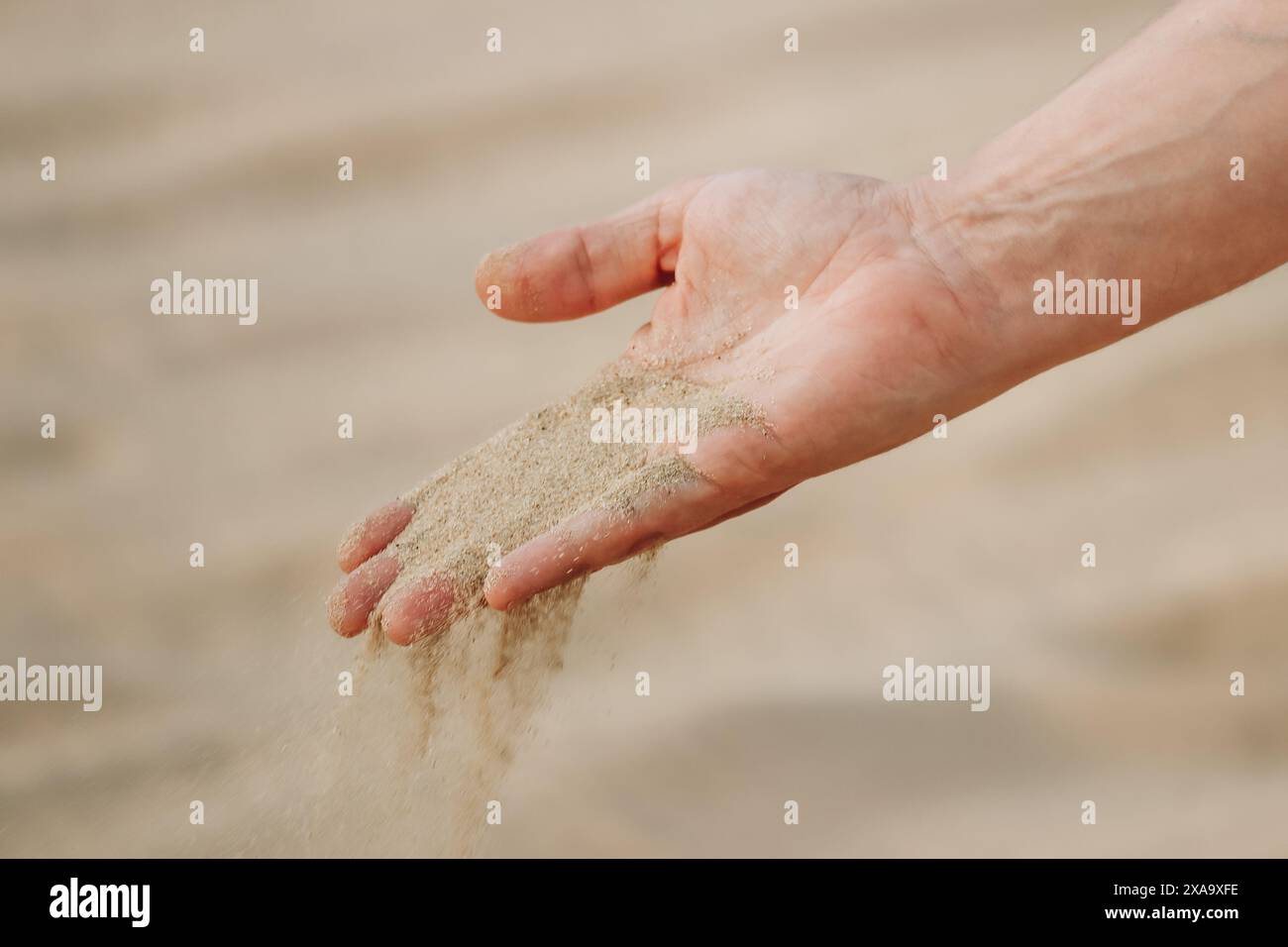 A man's hand pouring sand in the desert in Qatar Stock Photo - Alamy