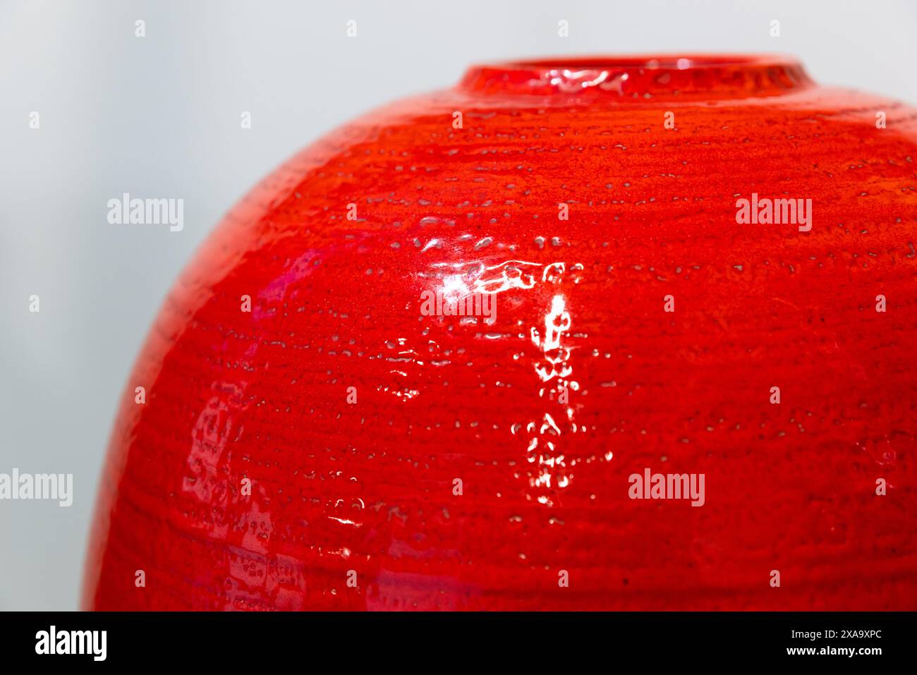 An empty round red vase stands in front of white wall, close up photo ...