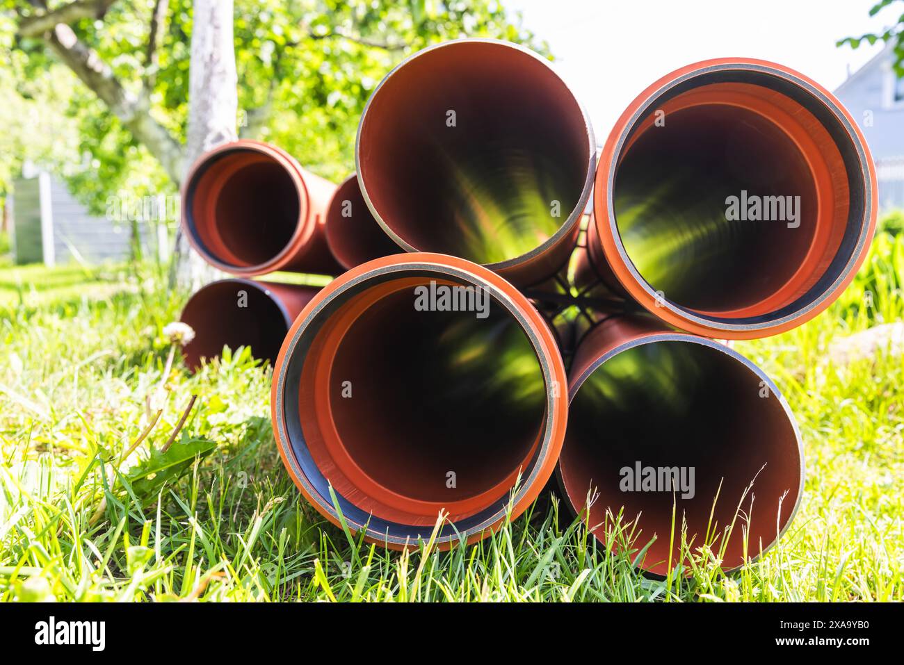 Pipes for external sewerage lay on grass on a sunny day, perspective ...