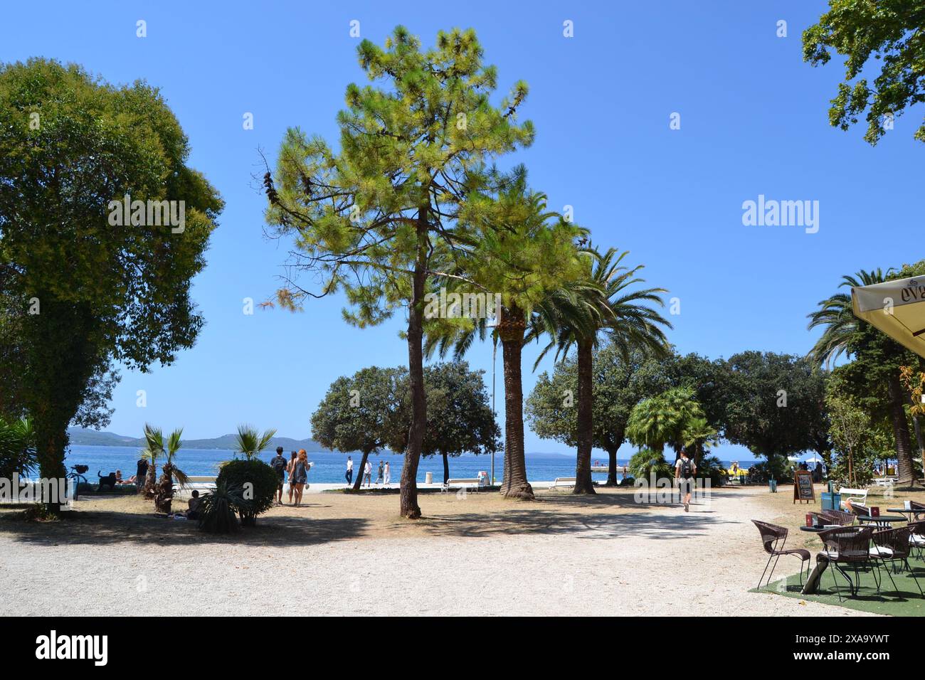 An outdoor park setting with tables and umbrellas by the beach Stock ...