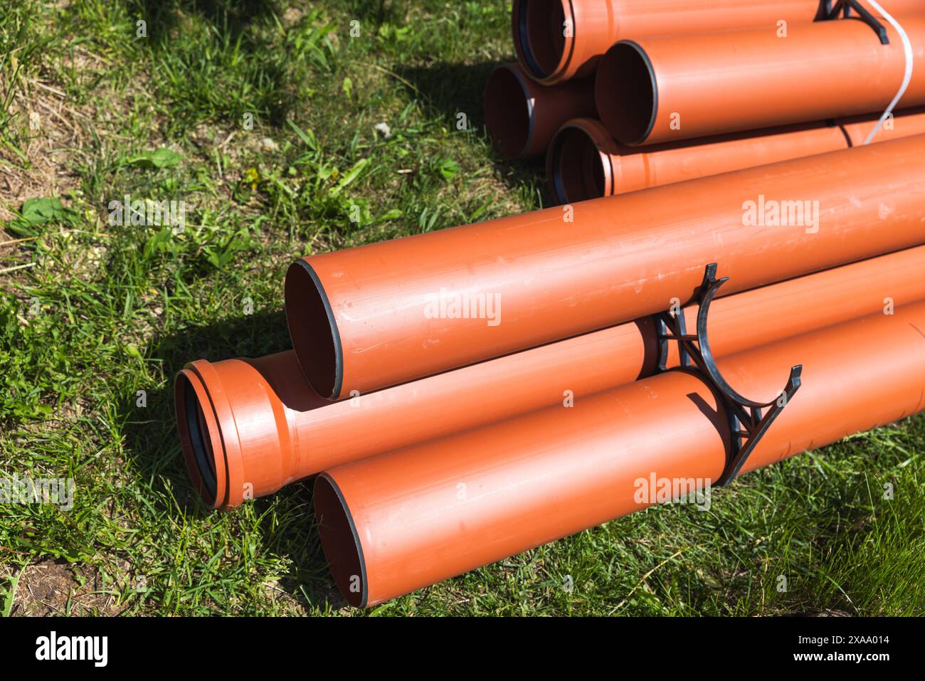 Pipes for external sewerage lay on grass on a sunny day, elements of ...