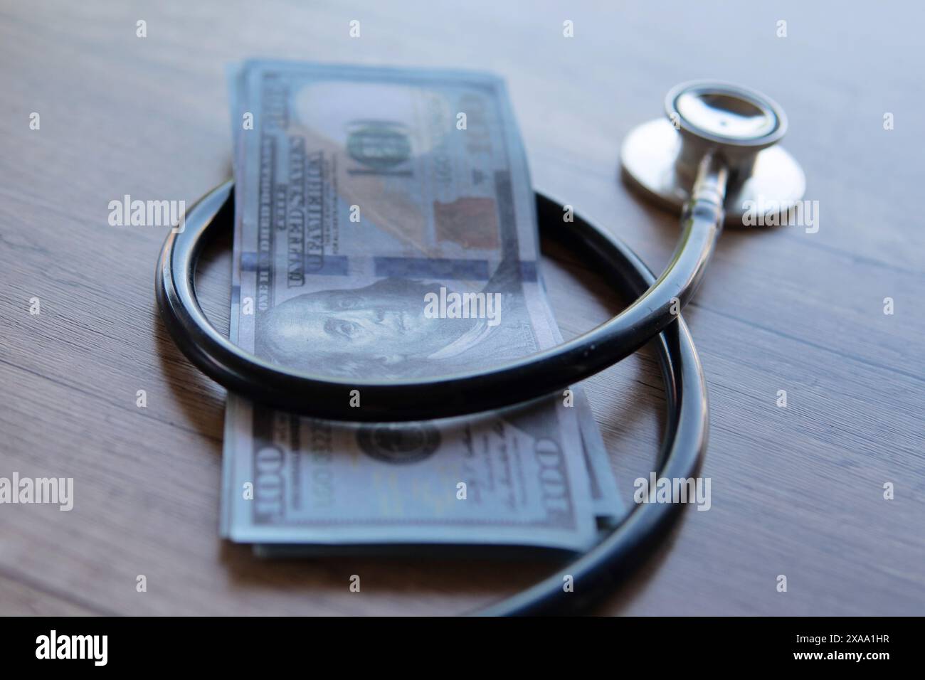 A close-up image of a black stethoscope wrapped around a stack of U.S ...