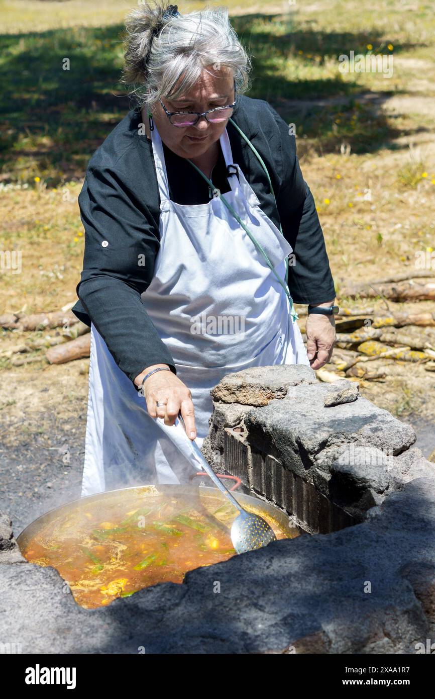woman cook with white apron cooking a typical Spanish paella on the ...