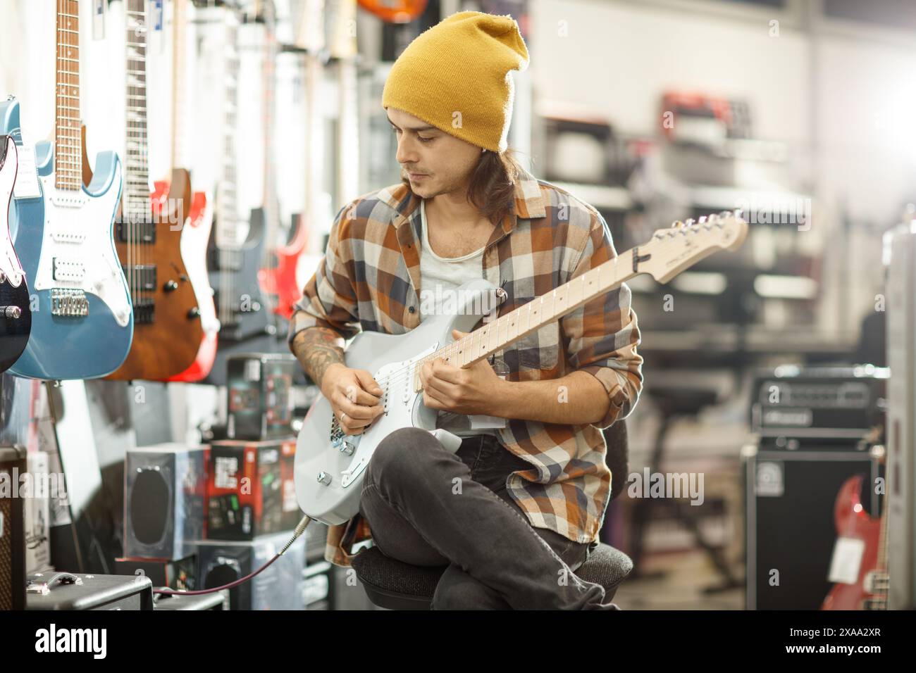 Young man playing an electric guitar in a musical instruments store ...