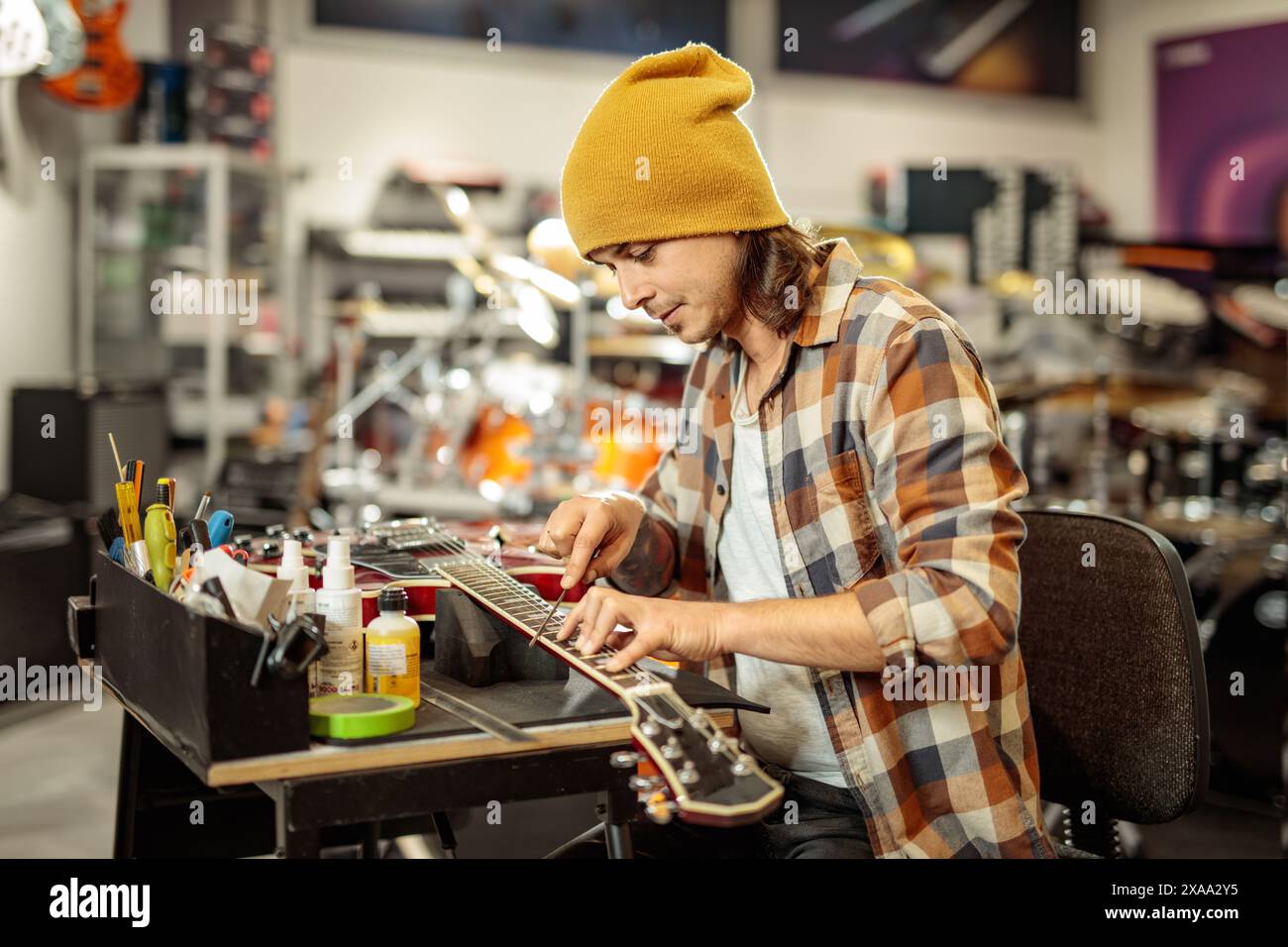 Young man repairing an electric guitar in a workshop Stock Photo - Alamy