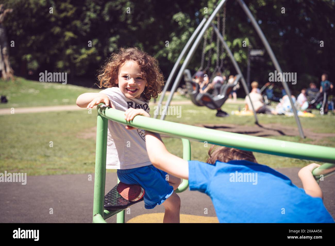5 year old girl playing on roundabout in sunny park Stock Photo - Alamy