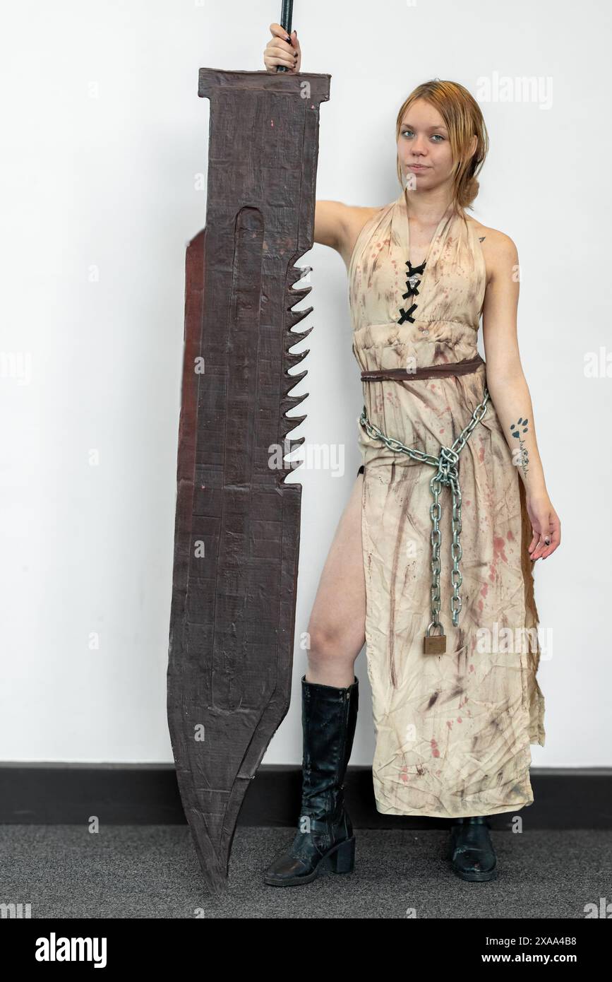 A female cosplayer in a horror outfit posing with a large blade sword ...