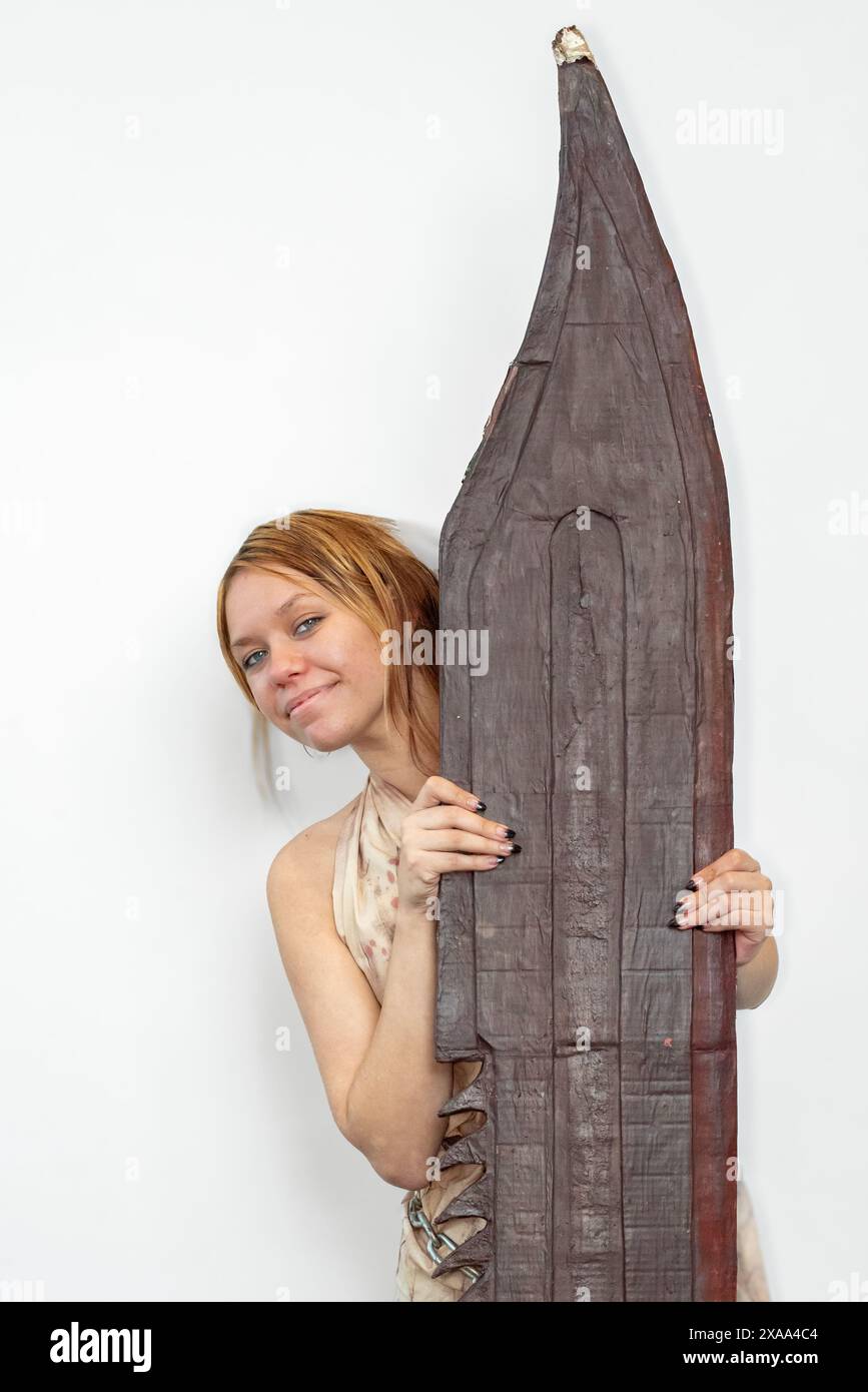 A female cosplayer in a horror outfit posing with a large blade sword ...