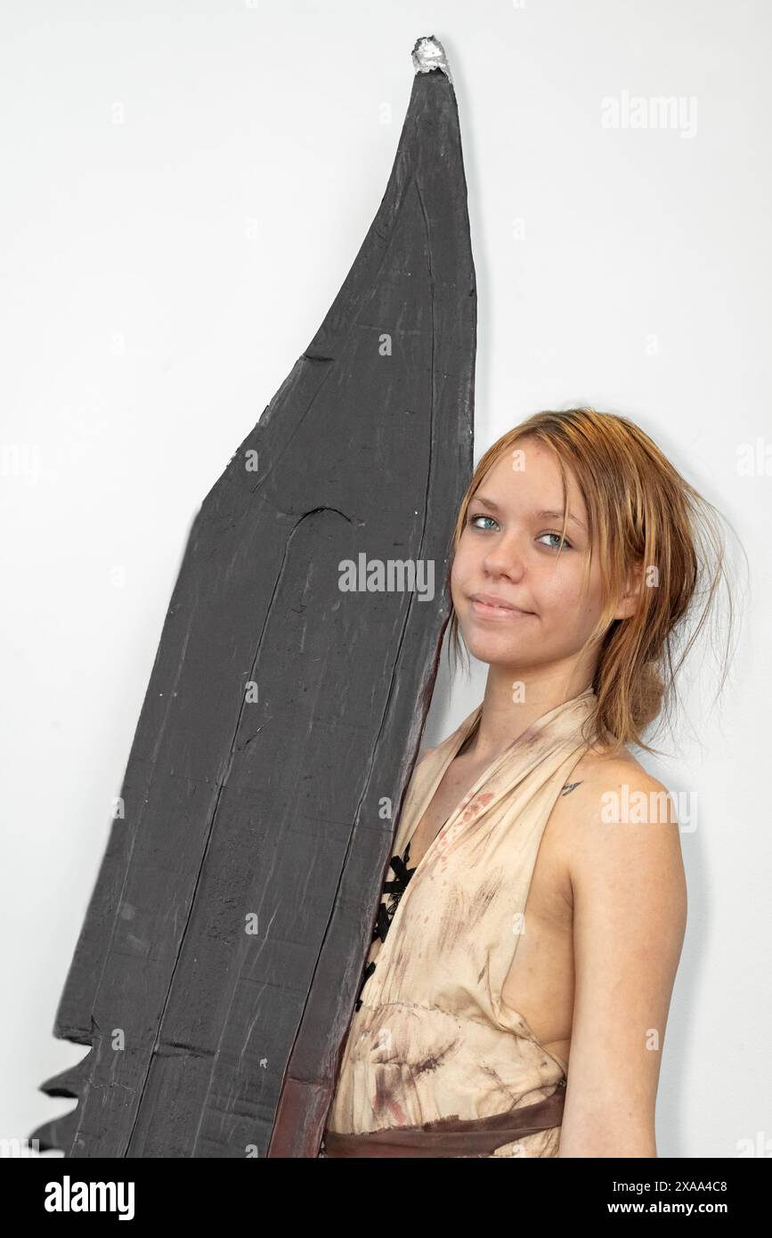 A female cosplayer in a horror outfit posing with a large blade sword ...