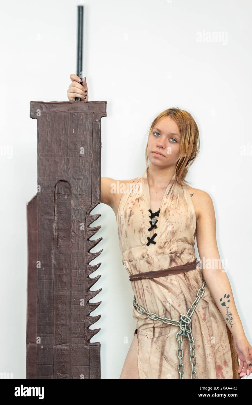 A female cosplayer in a horror outfit posing with a large blade sword ...