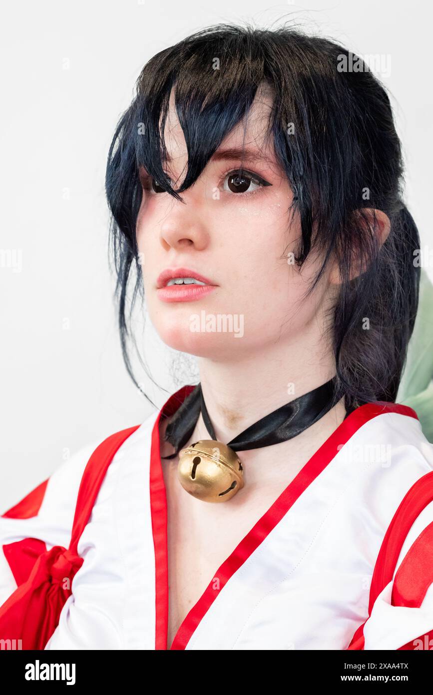 A female cosplayer in a white and red outfit with black hair and a bell ...