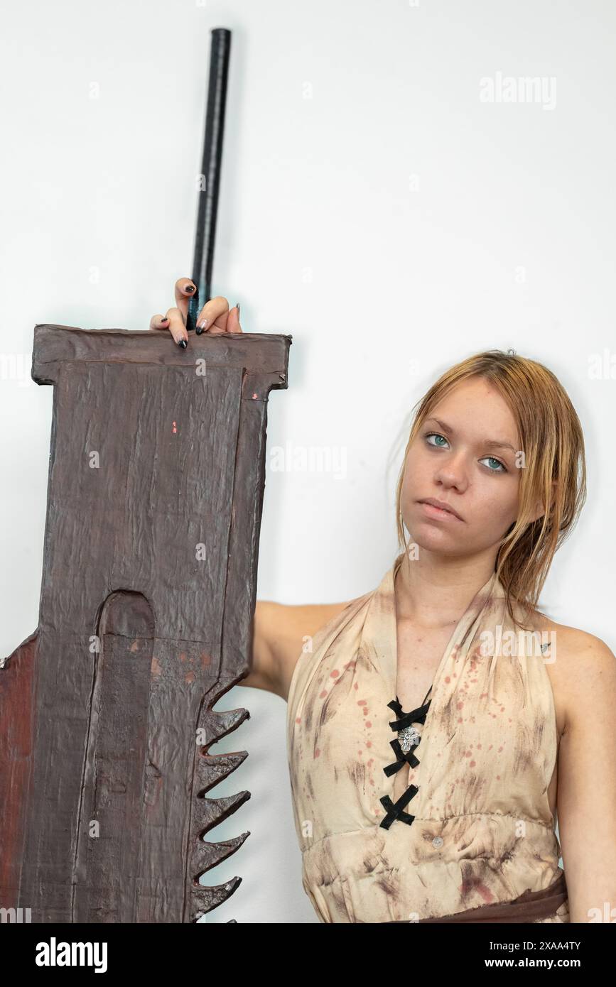A female cosplayer in a horror outfit posing with a large blade sword ...