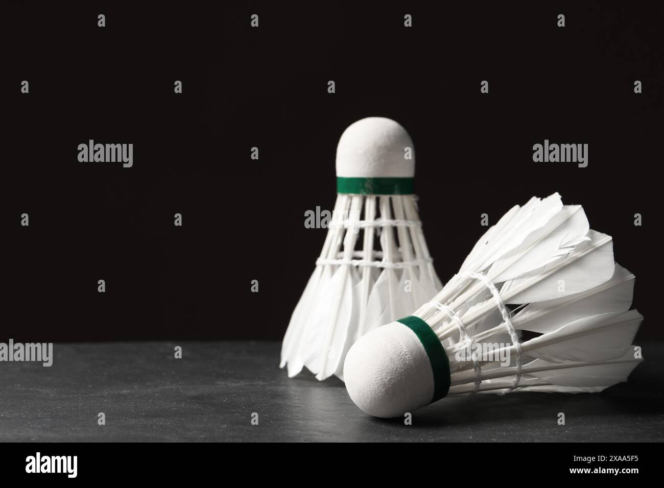 Feather badminton shuttlecocks on grey table against black background ...