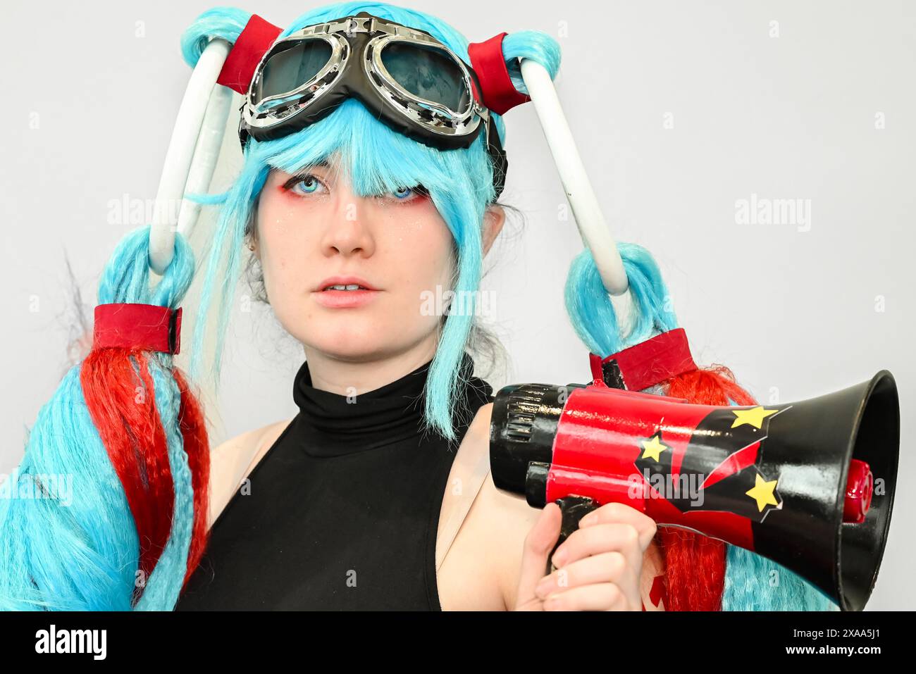 A female cosplayer dressed as an anime character with blue hair and a ...