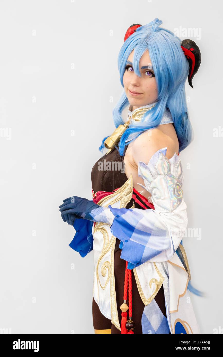 A female cosplayer with blue hair and an elaborate dress posing against ...