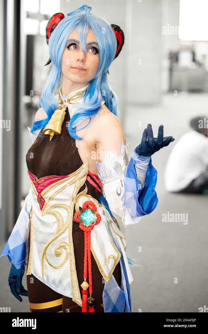 A female cosplayer with blue hair and an elaborate dress posing against ...