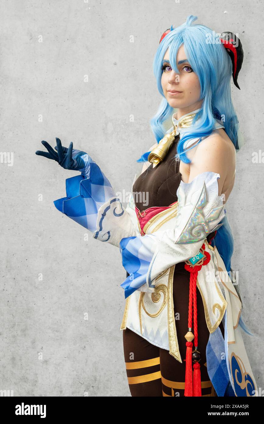 A female cosplayer with blue hair and an elaborate dress posing against ...