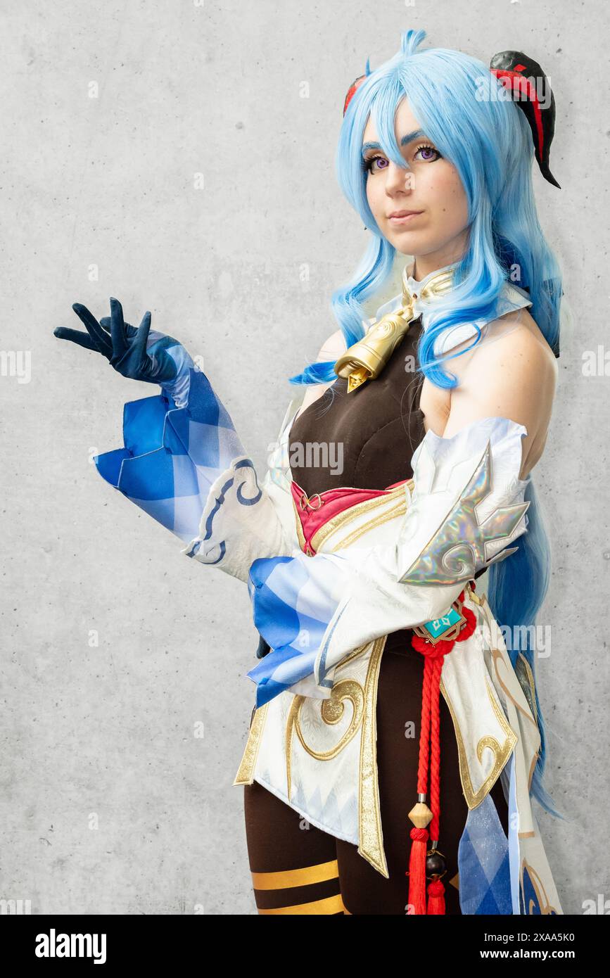 A female cosplayer with blue hair and an elaborate dress posing against ...