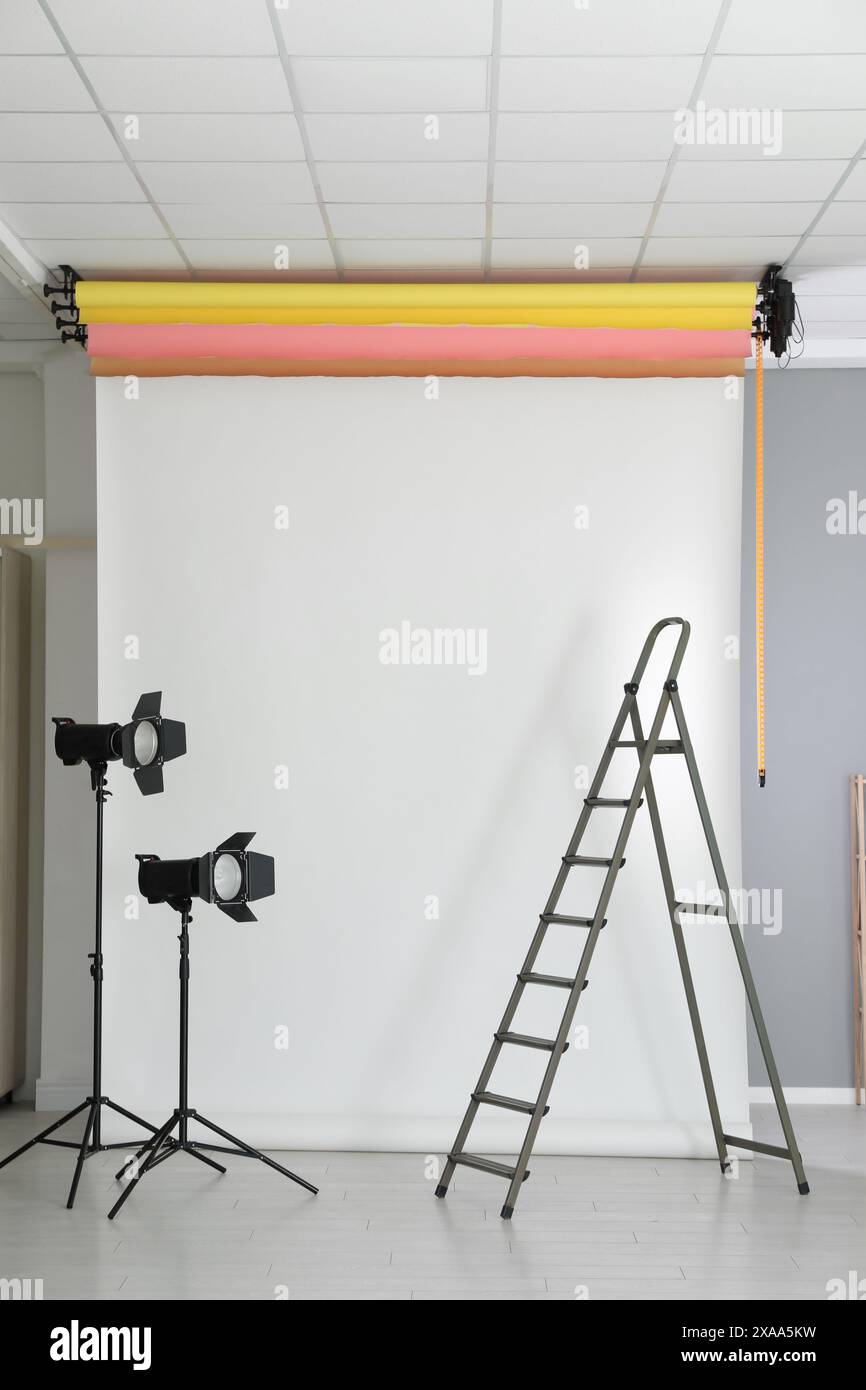 White photo background, ladder and professional lighting equipment in ...