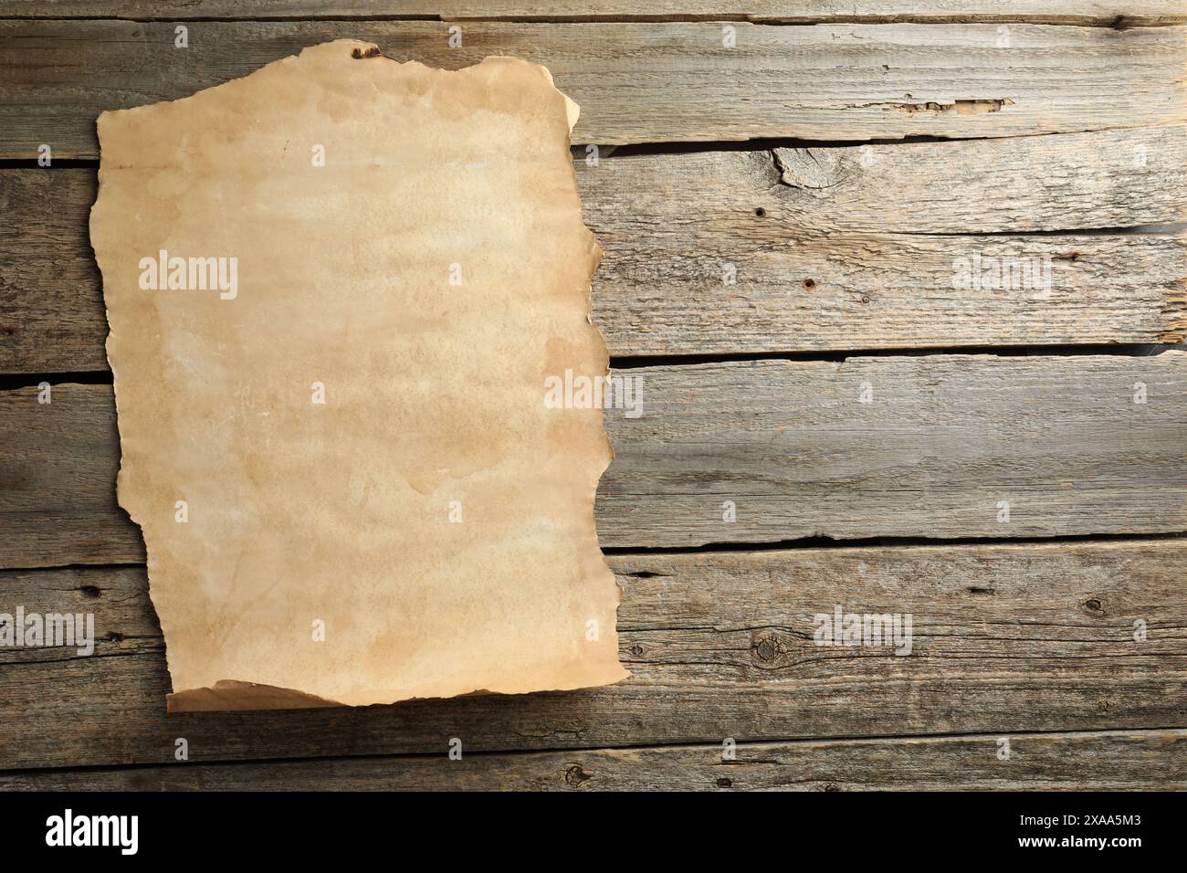 Sheet of old parchment paper on wooden table, top view. Space for text ...