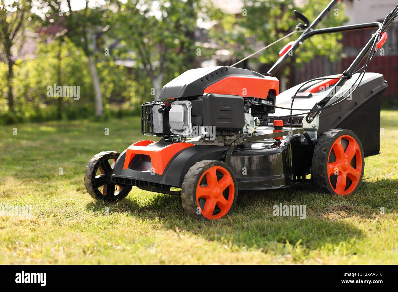 Modern lawn mower on green grass in garden Stock Photo - Alamy