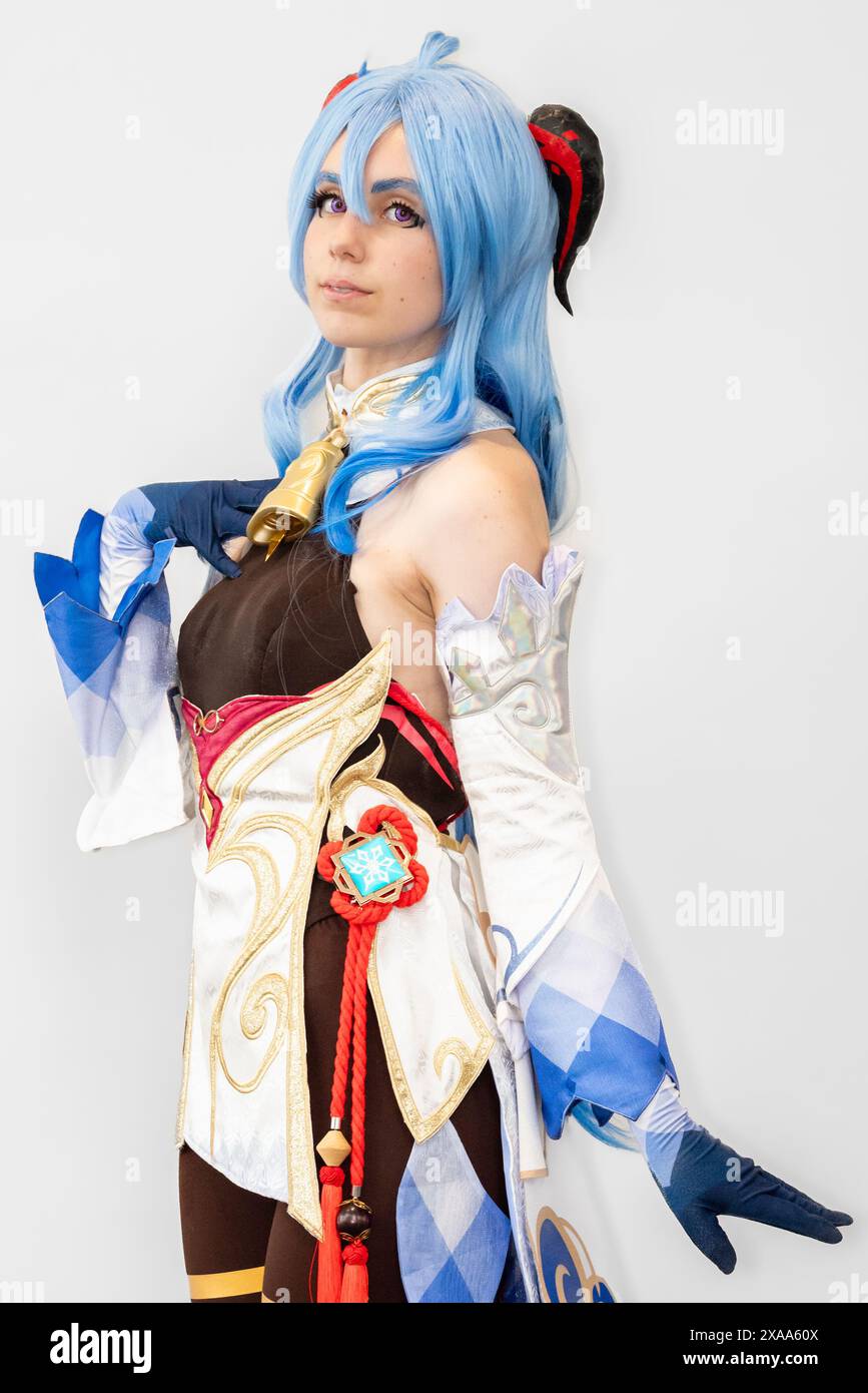 A female cosplayer with blue hair and an elaborate dress posing against ...