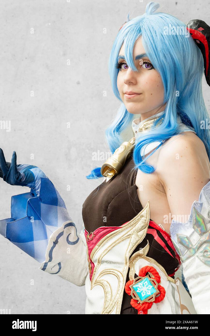 A female cosplayer with blue hair and an elaborate dress posing against ...