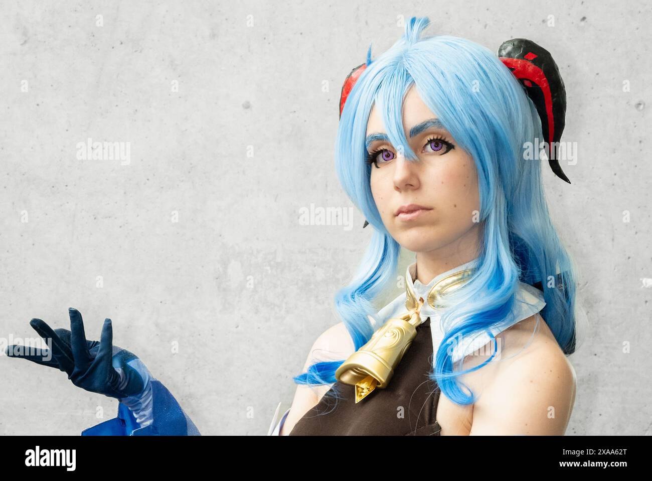 A female cosplayer with blue hair and an elaborate dress posing against ...
