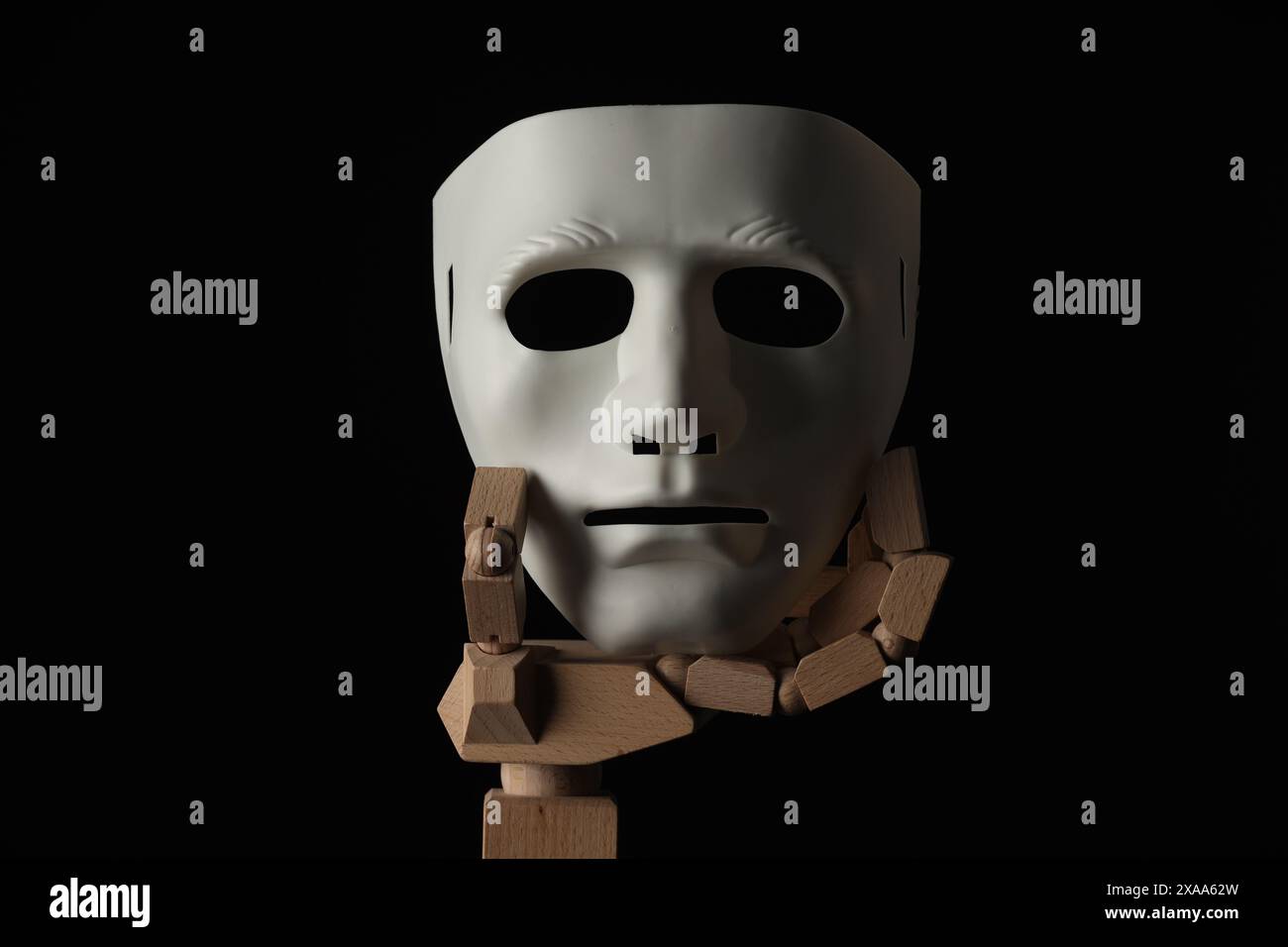 Wooden mannequin hand holding plastic mask on black background ...