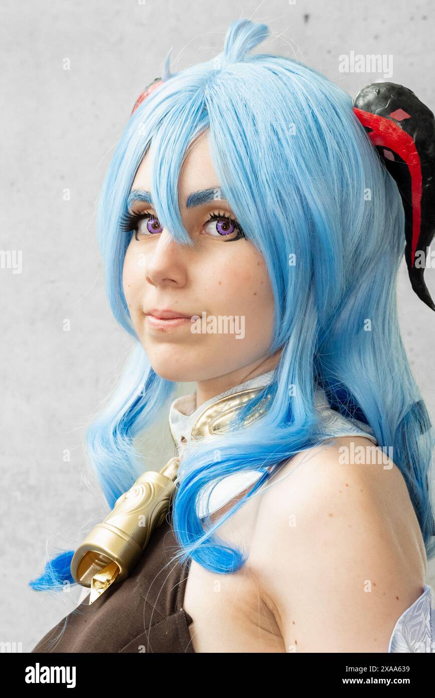 A female cosplayer with blue hair and an elaborate dress posing against ...
