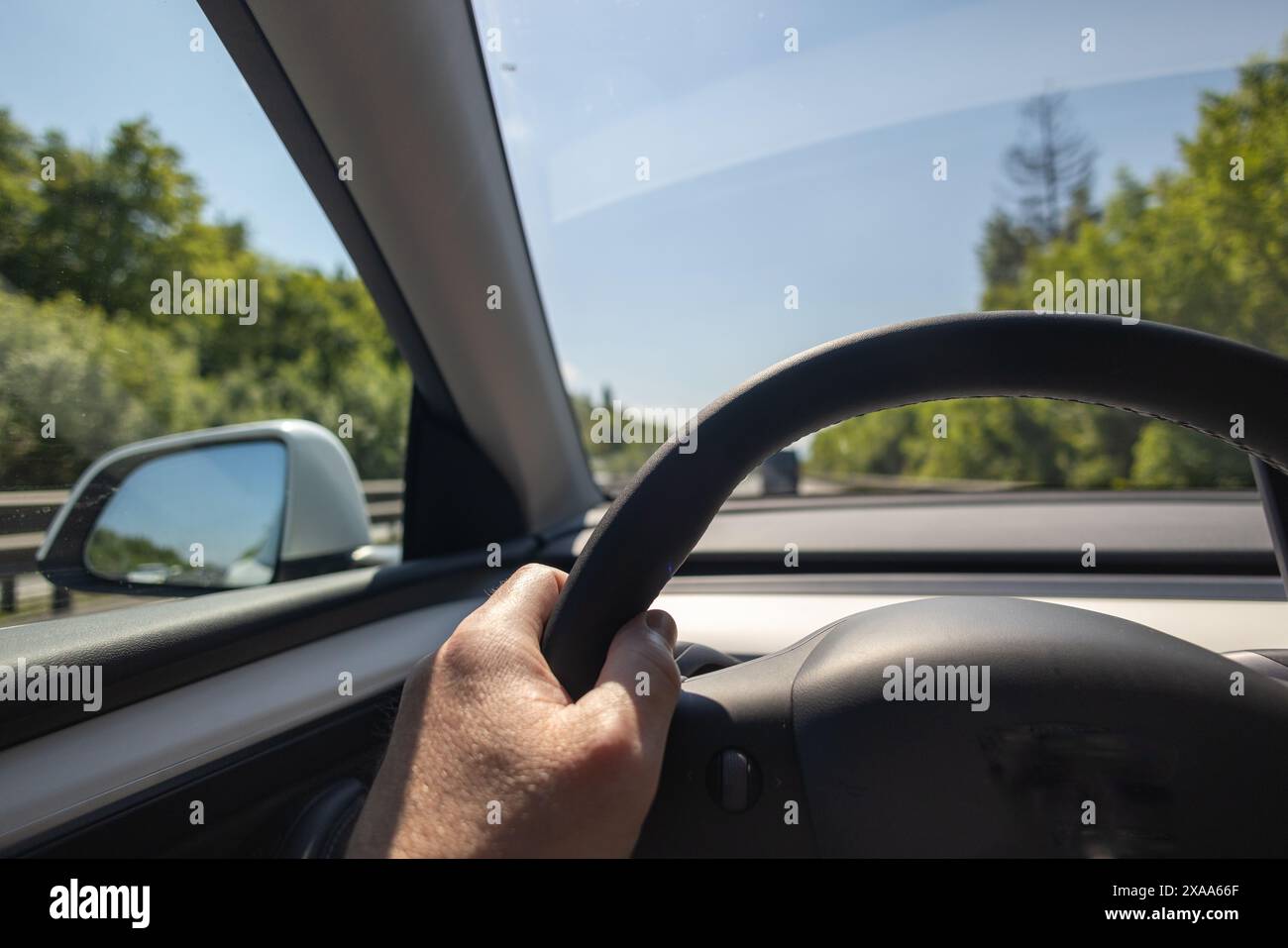 A driver gripping steering wheel while driving on the highway beside ...